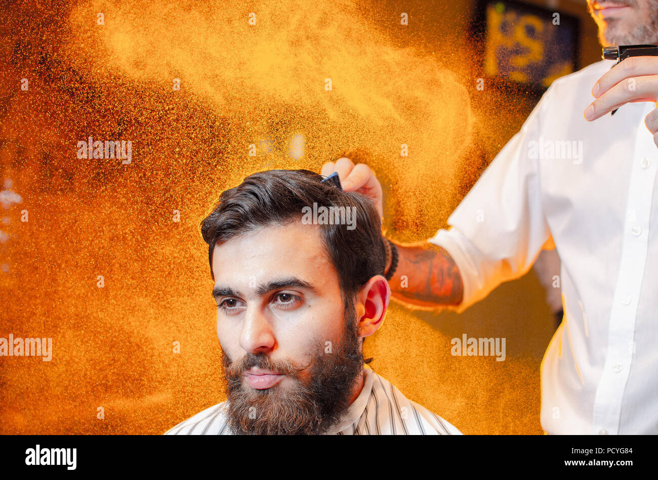 Barber combs his hair to a young guy with a beard and mustache and ...