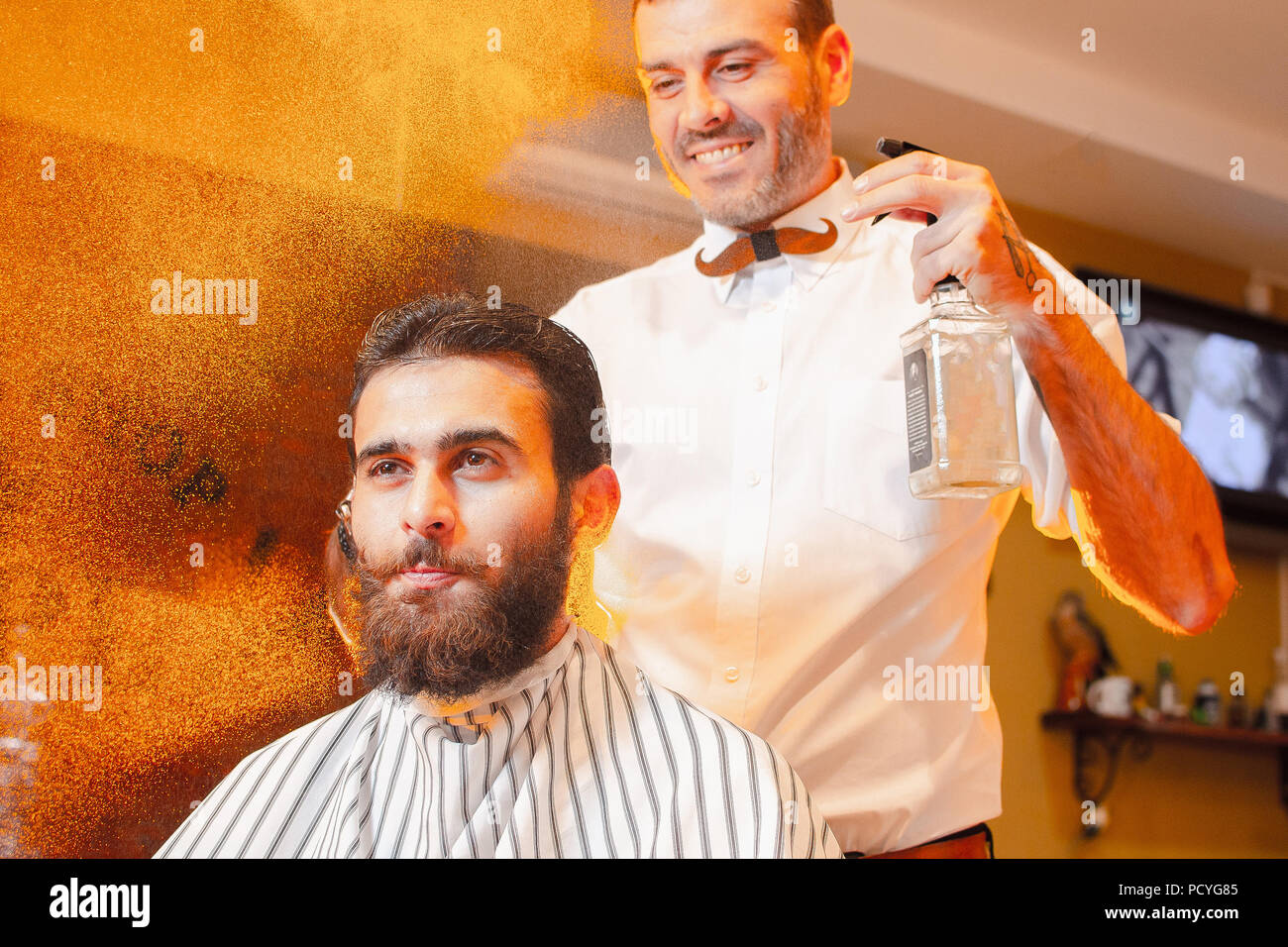 Barber combs his hair to a young guy with a beard and mustache and ...