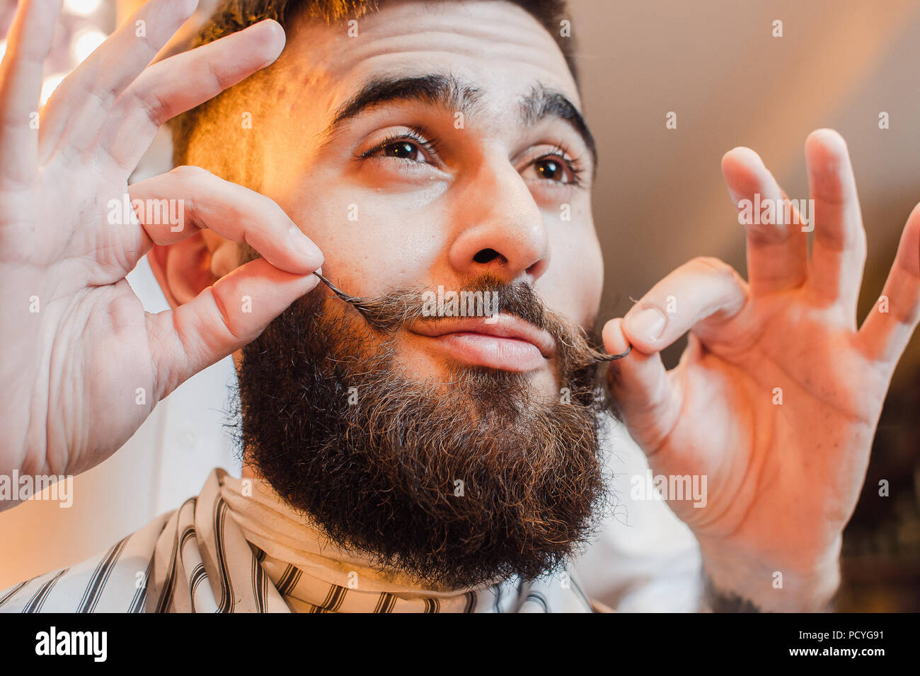 Barber makes a styling mustache for a young handsome guy in a male ...