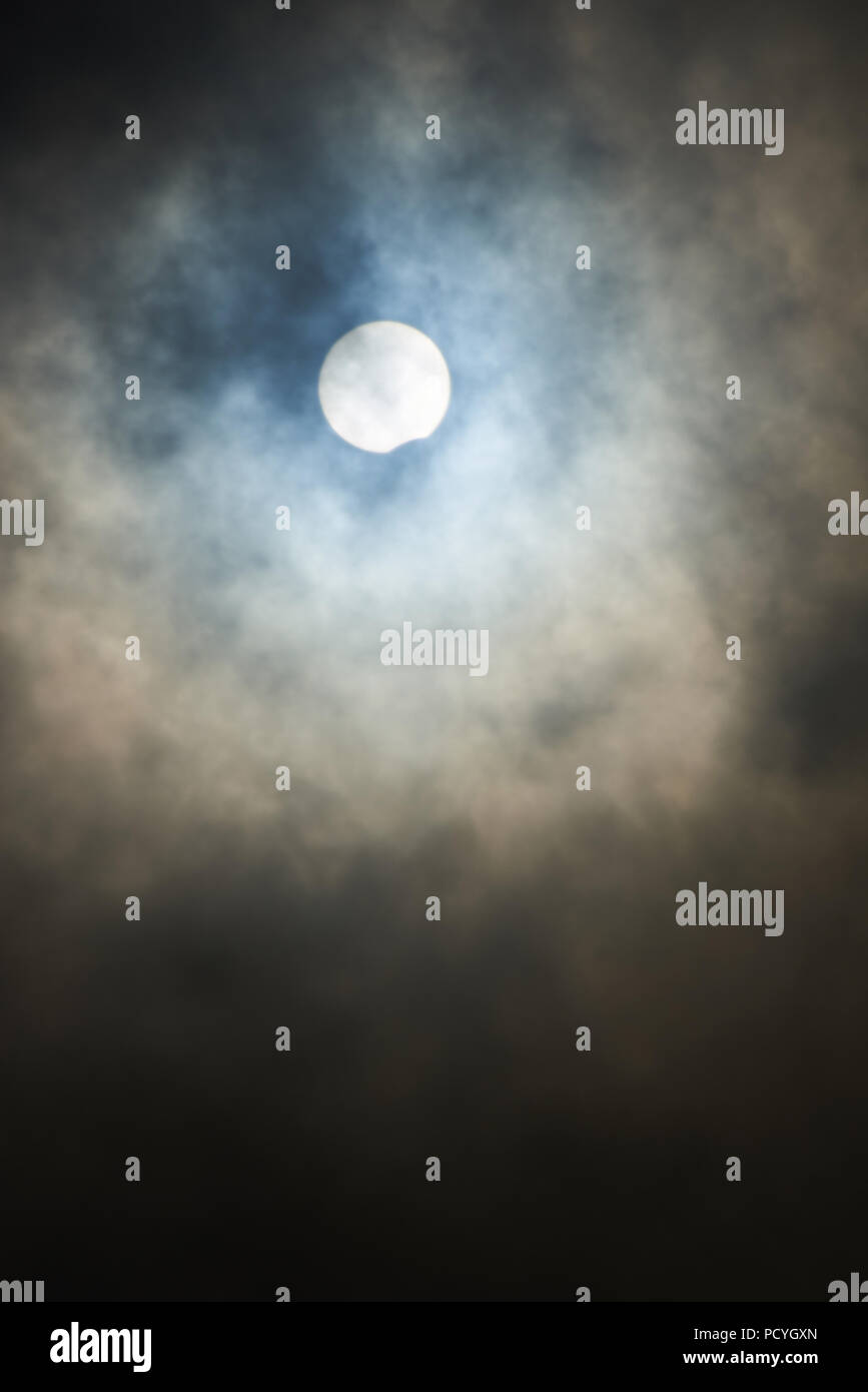 Partial solar eclipse background on bright cloudy sky Stock Photo - Alamy