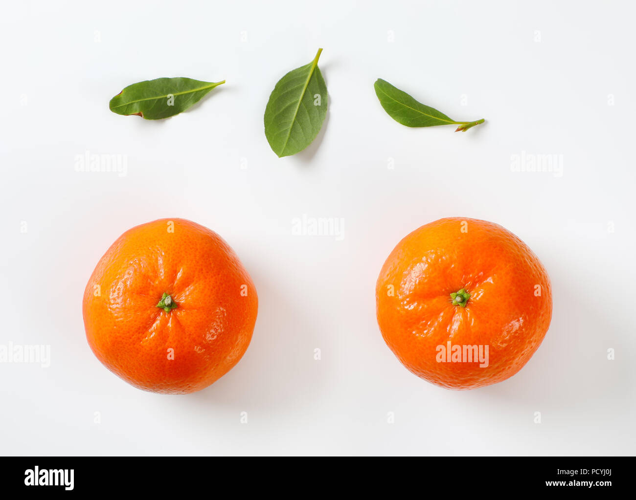 two ripe tangerines and leaves on white background Stock Photo - Alamy