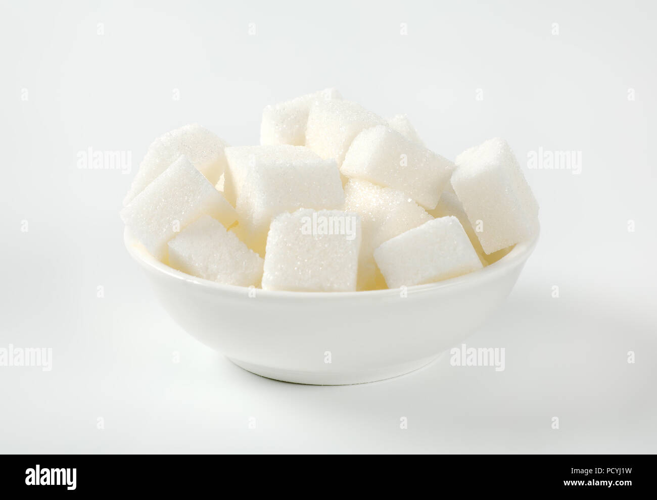 bowl of white sugar cubes on white background Stock Photo - Alamy