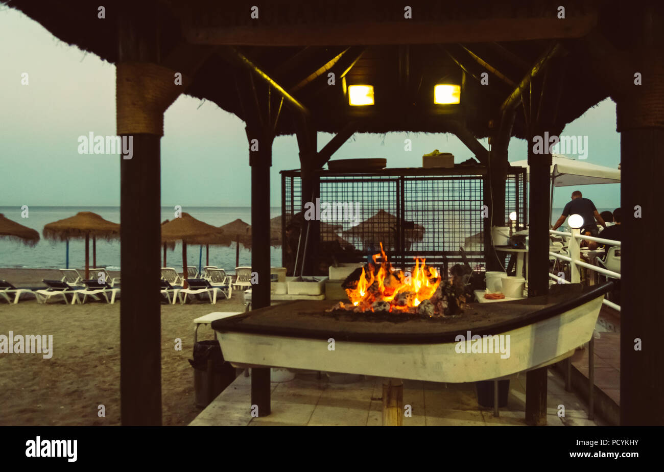 Boat in the beach with fire to roast fish to the firewood. Typical ...