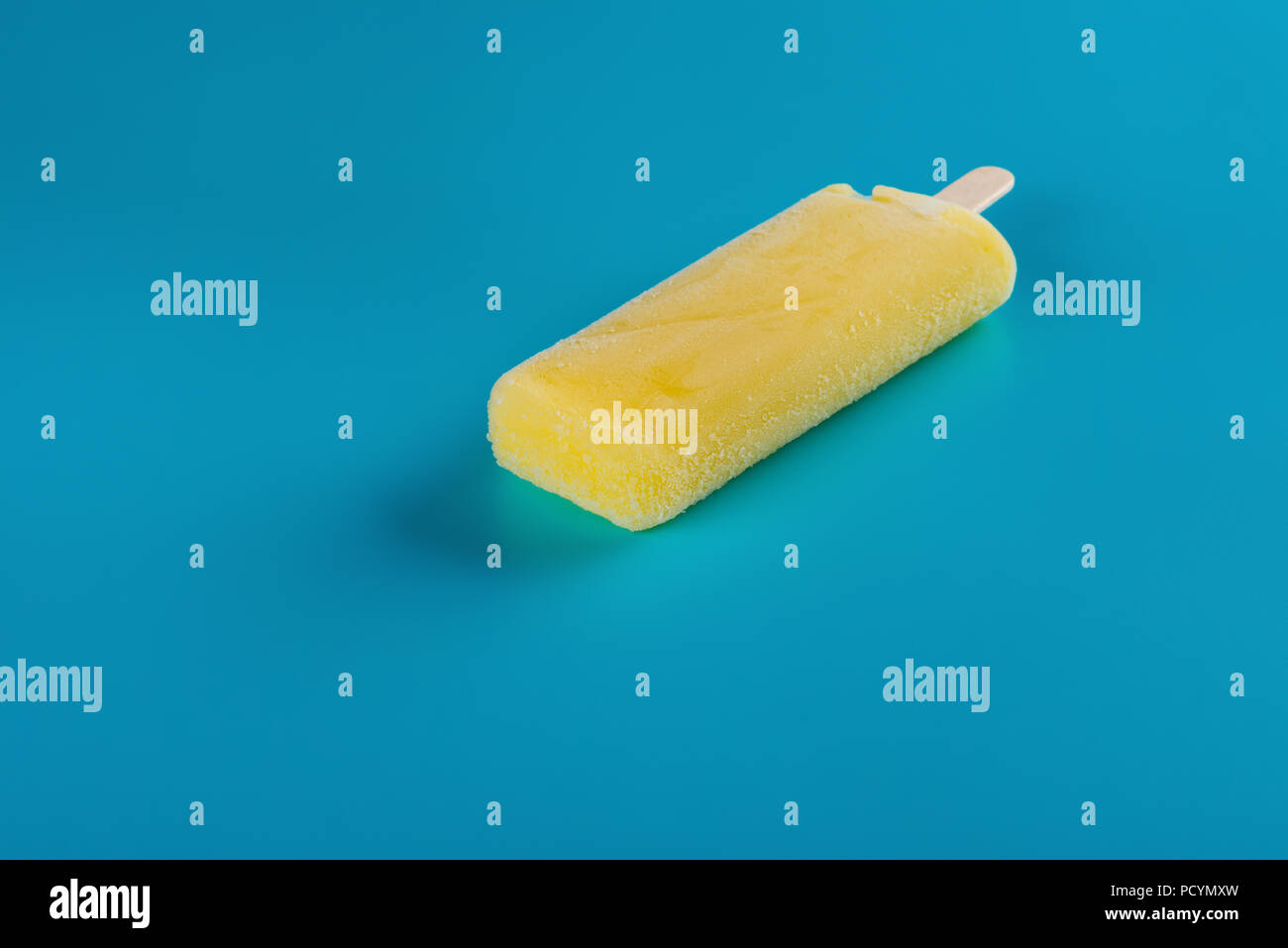 side view yellow popsicle on a blue background Stock Photo - Alamy