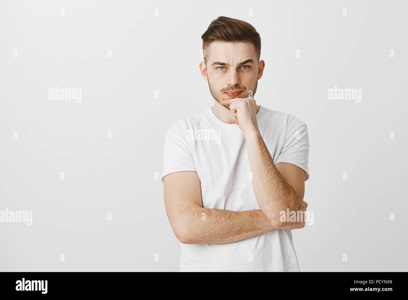 Studio shot of intense unsure stylish male model with cool hairstyle in ...
