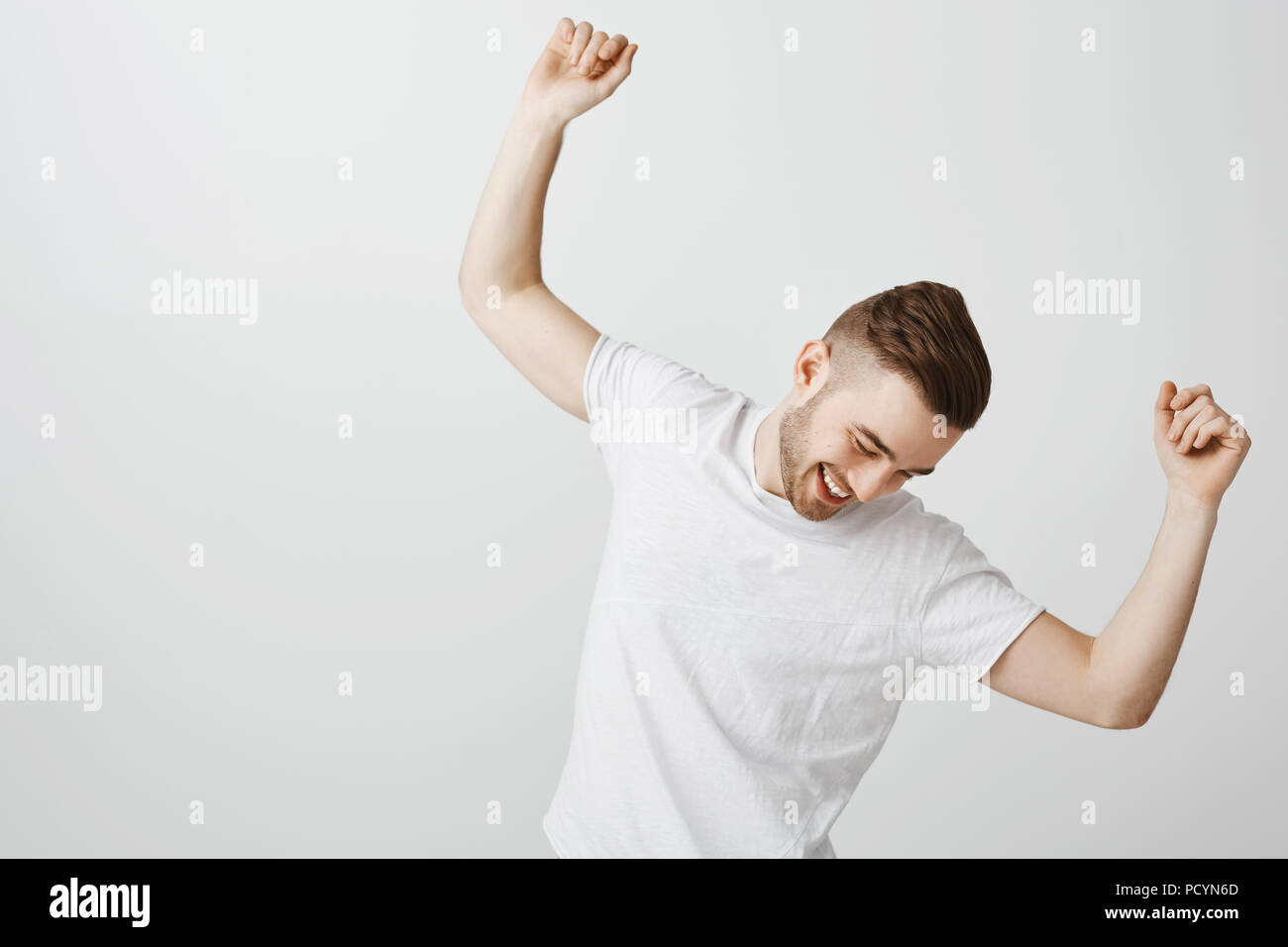 Happy and pleased good-looking guy with beard in white t-shirt ...