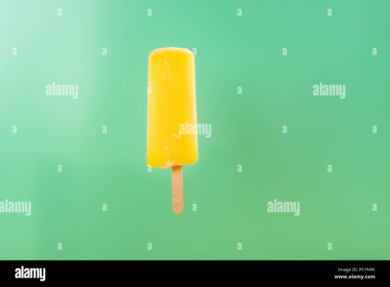 yellow popsicle on a light green background Stock Photo - Alamy