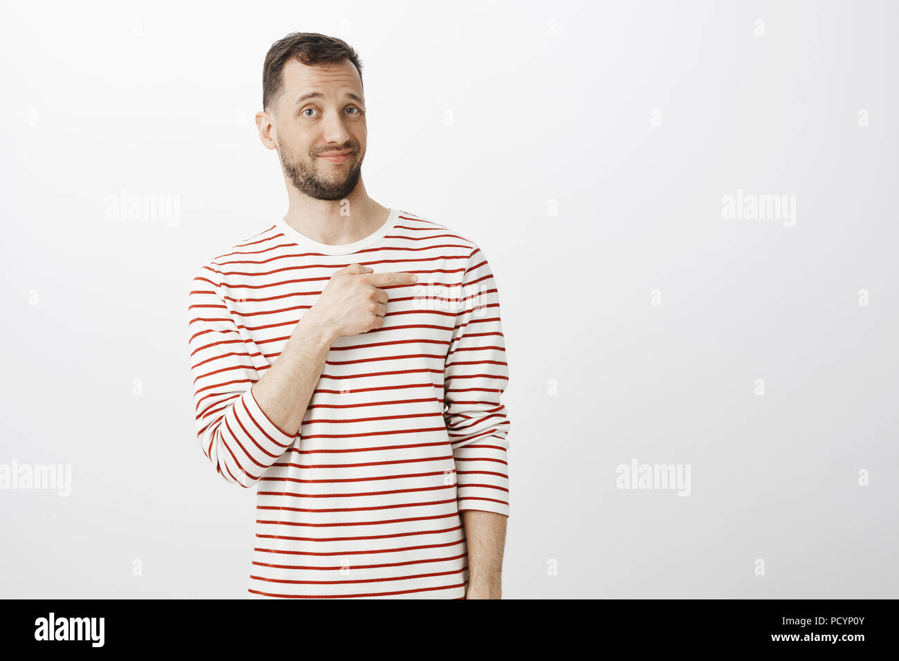 Portrait of unsure hesitating attractive man with beard, pointing right ...
