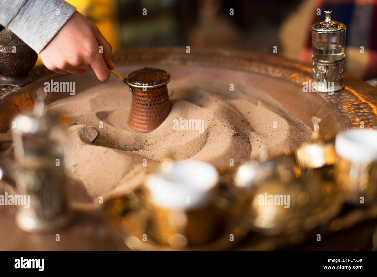 Cooking Turkish coffee in sand and a cezve. Turkish coffeee is a ...