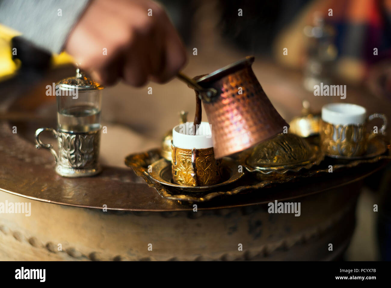 Serving Turkish coffee which cooked in hot sand from a copper cezve to ...