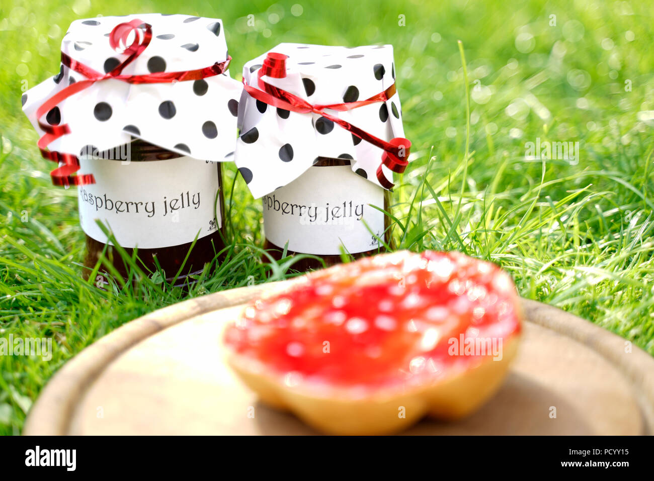 2 glasses with homemade raspberry jelly stand on sunny green meadow ...