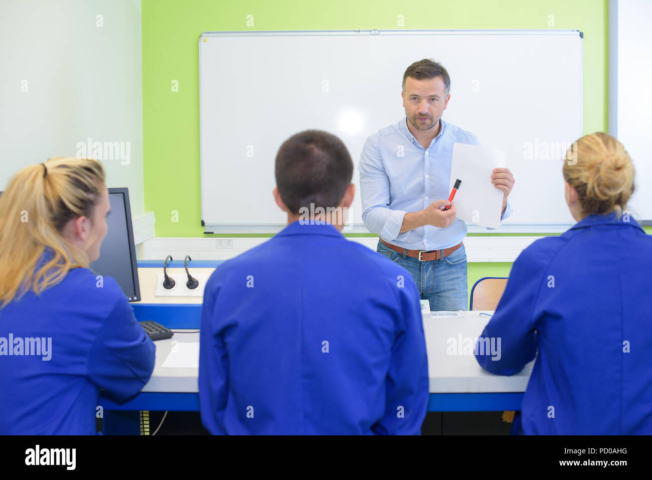 Teacher holding paper towards class Stock Photo - Alamy