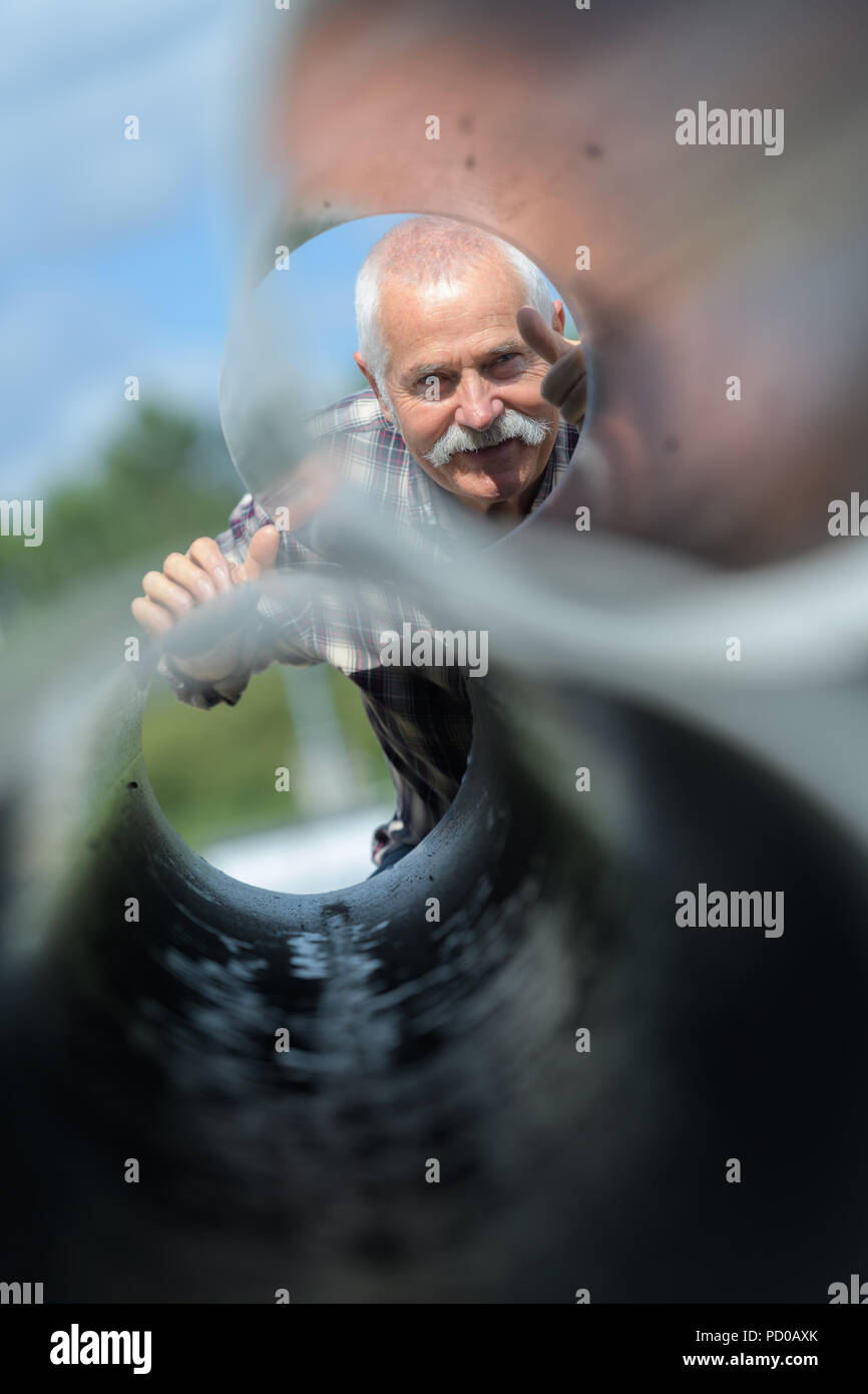 senior man looking through construction pipes Stock Photo - Alamy