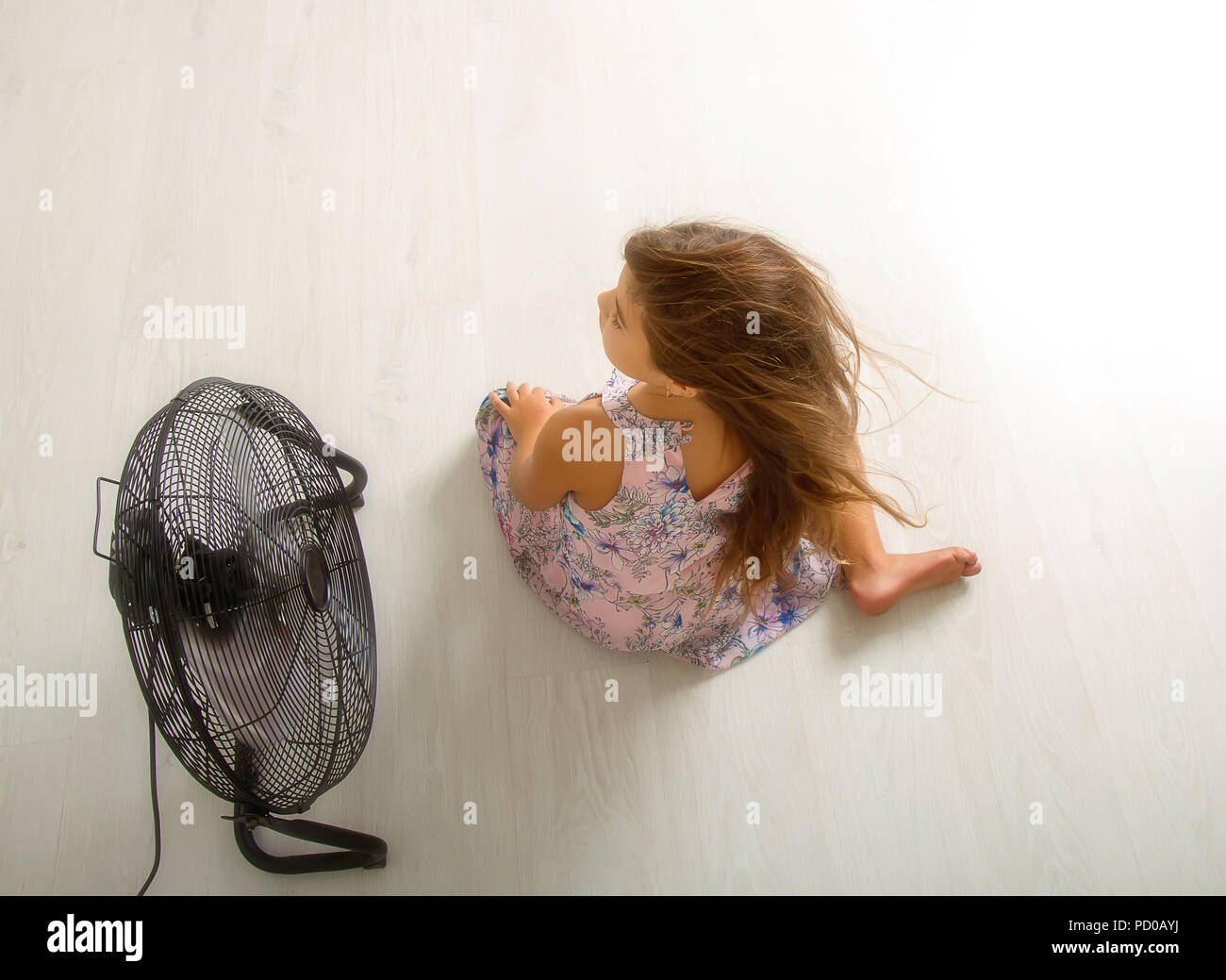 the girl is sitting in front of the fan Stock Photo - Alamy