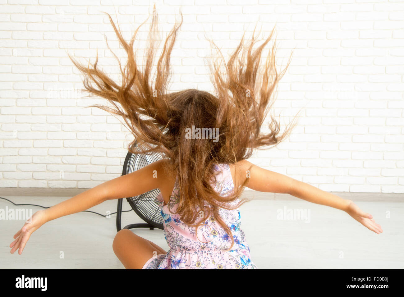 the girl is sitting in front of the fan Stock Photo - Alamy