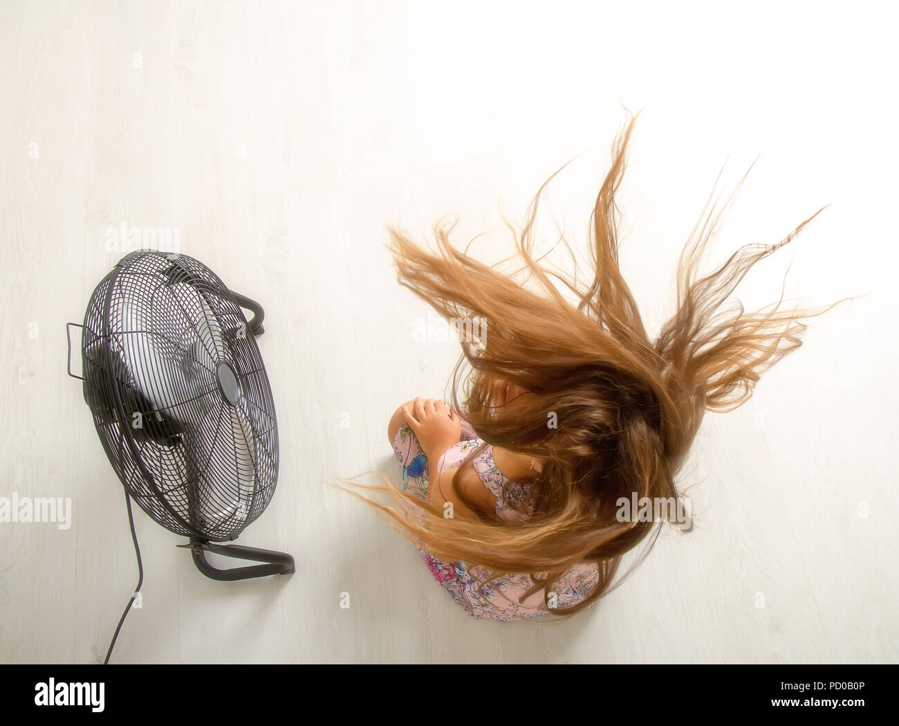 the girl is sitting in front of the fan Stock Photo - Alamy