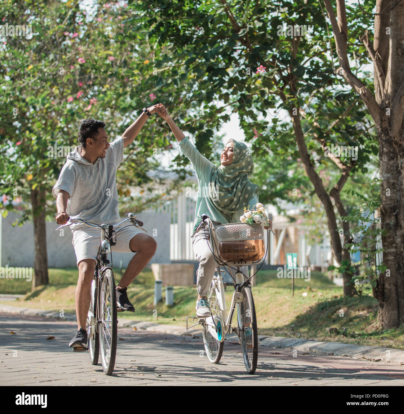 couple holding hands while ride a bike Stock Photo - Alamy