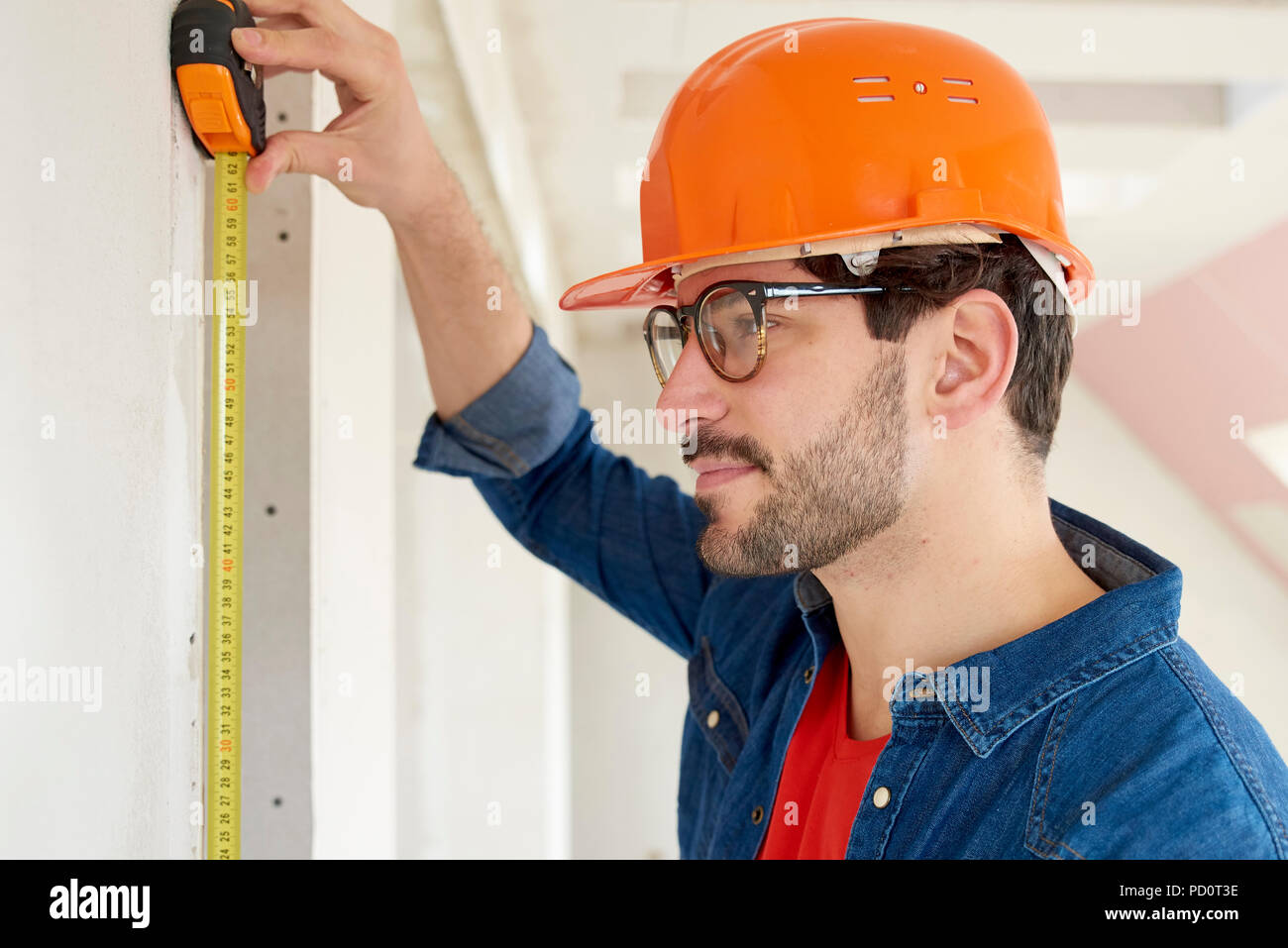Portrait of young man using measuring tape while working on ...