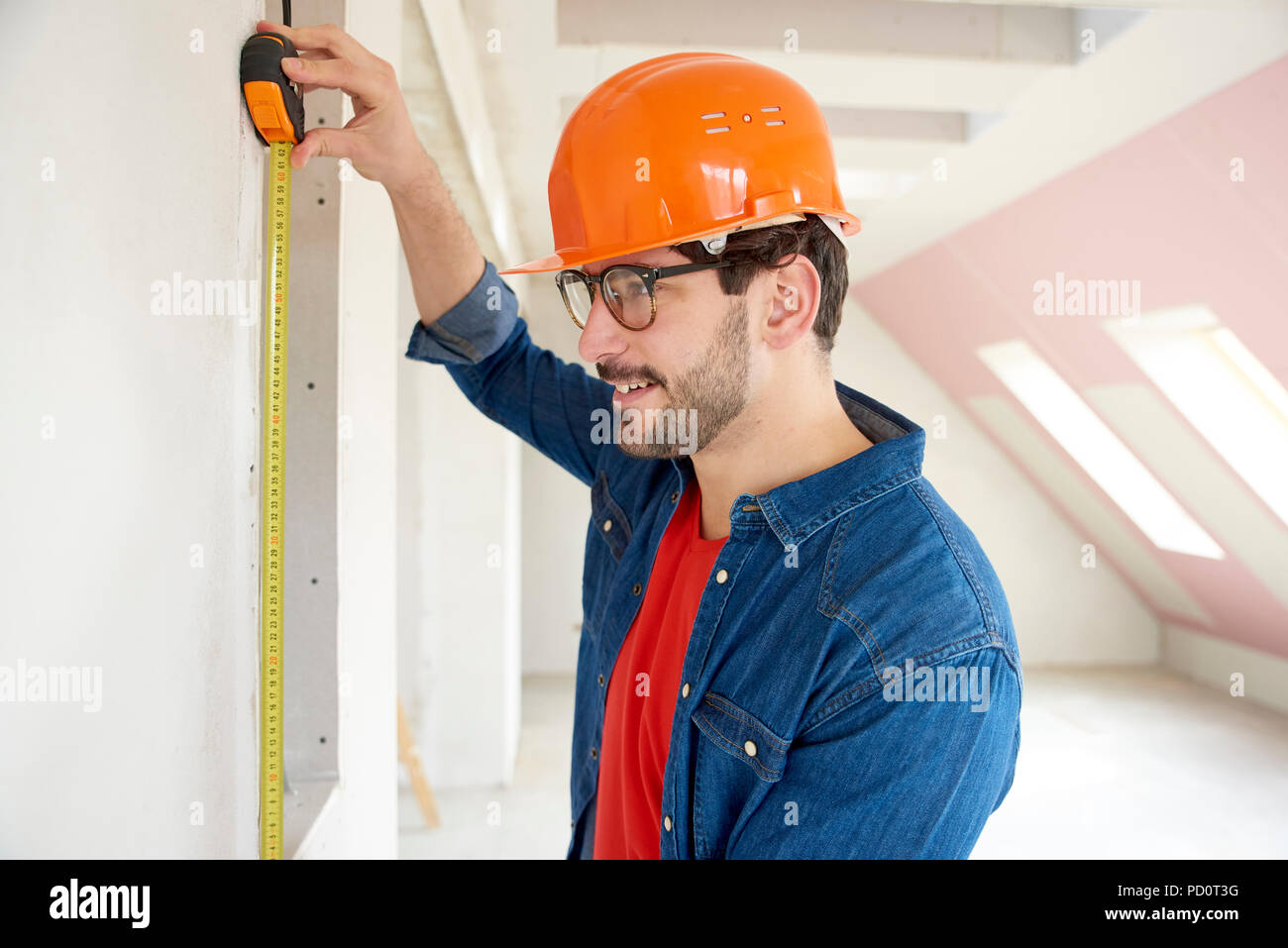 Portrait of young man using measuring tape while working on ...