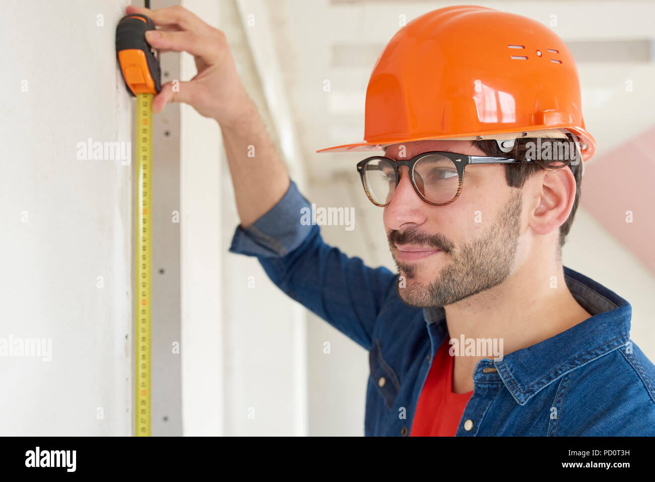 Close-up portrait of young man using measuring tape while working on ...