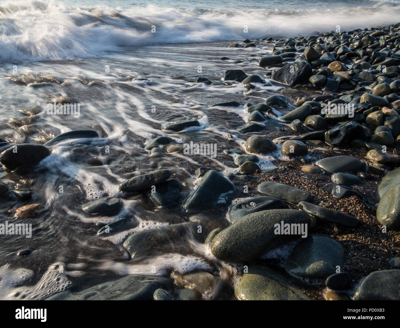 The ebb and flow of waves lapping a pebble beach Stock Photo - Alamy