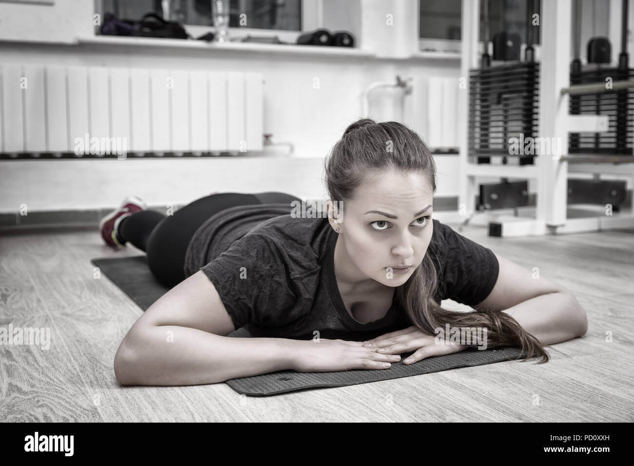 Portrait of young woman lying on mat while exercising at gym Stock ...