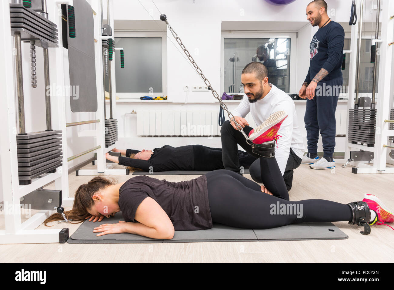 Two women exercising at gym using cable crossover machines with sport instructors Stock Photo ...