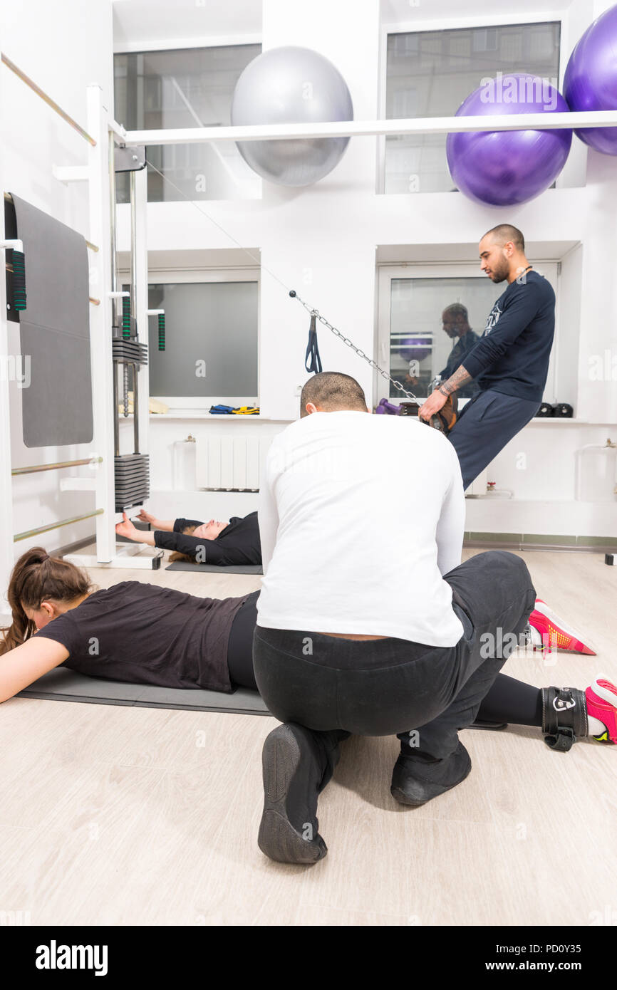 Two personal trainers working out with women toning and strengthening ...