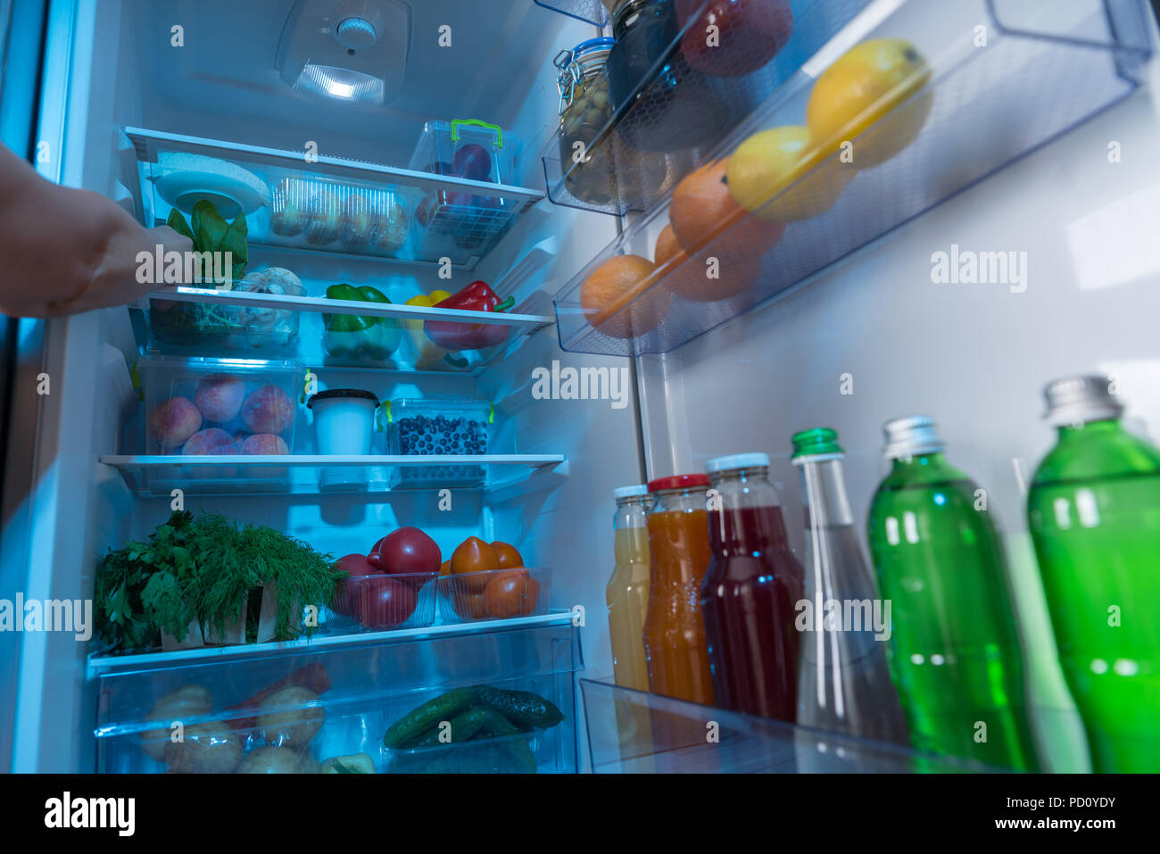 Person reaching into a refrigerator for fresh fruit and vegetables ...