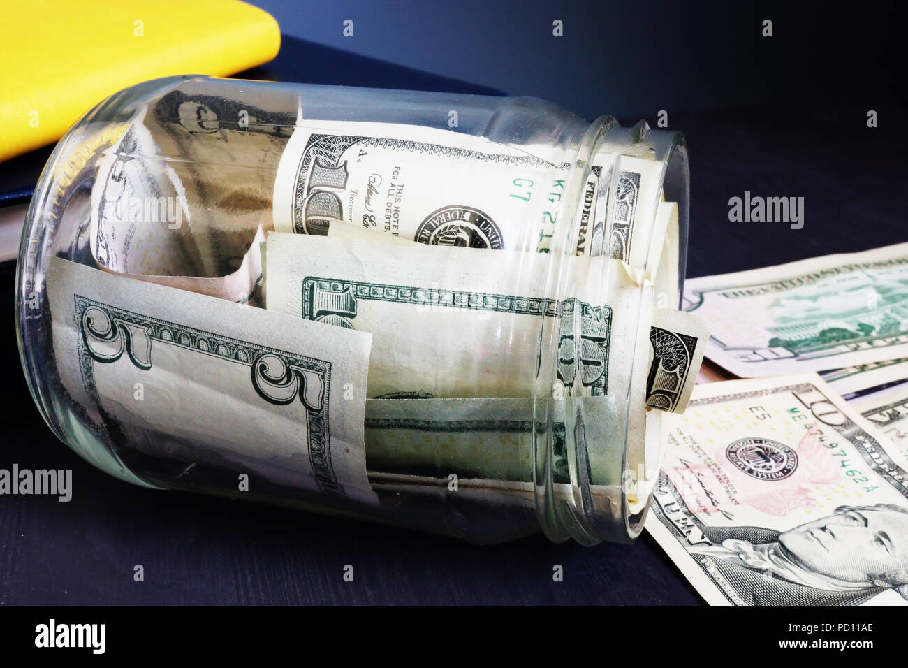 Savings. Jar with money. Dollar banknotes on a desk Stock Photo - Alamy