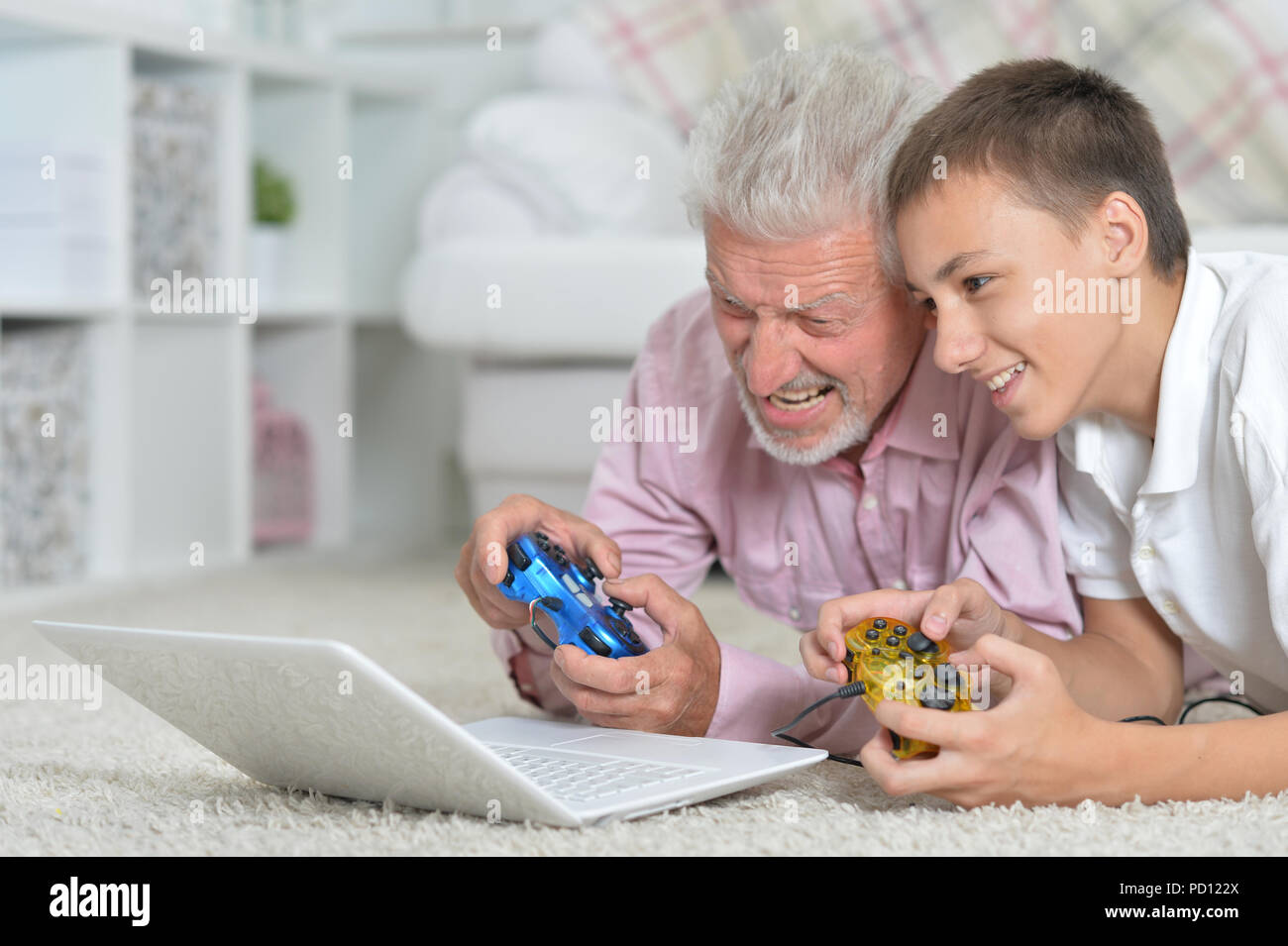 grandfather and grandson lying on floor and playing computer gam Stock ...