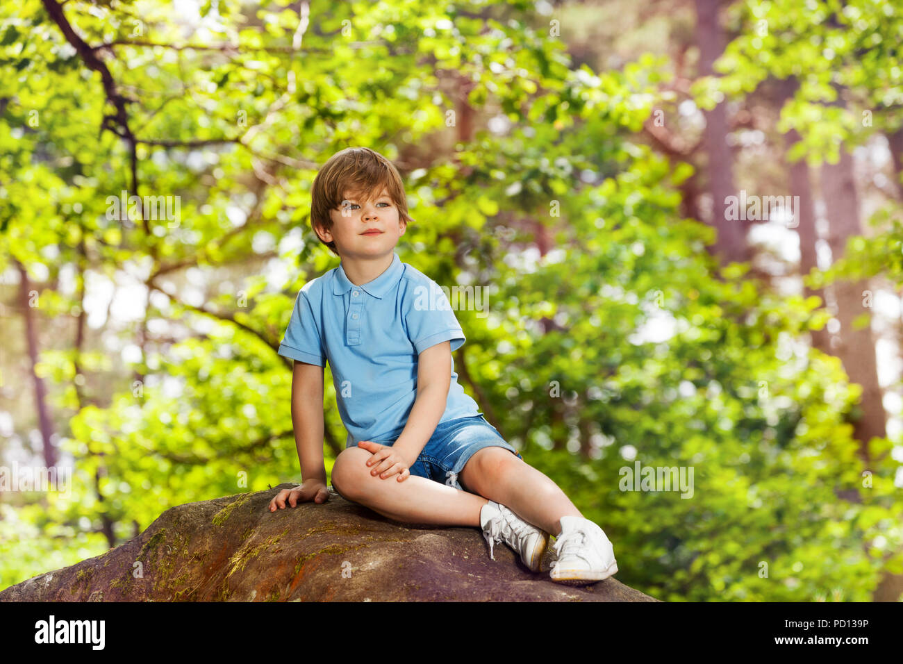 Little boy sit on stone in the forest Stock Photo - Alamy