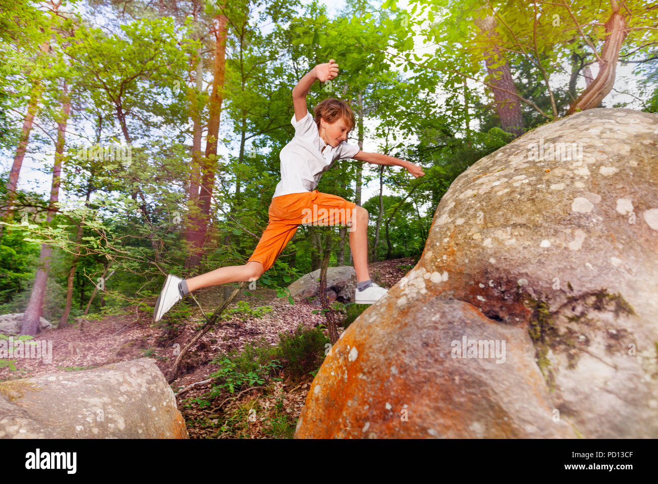 Mid air portrait of a boy jumping between rocks Stock Photo - Alamy