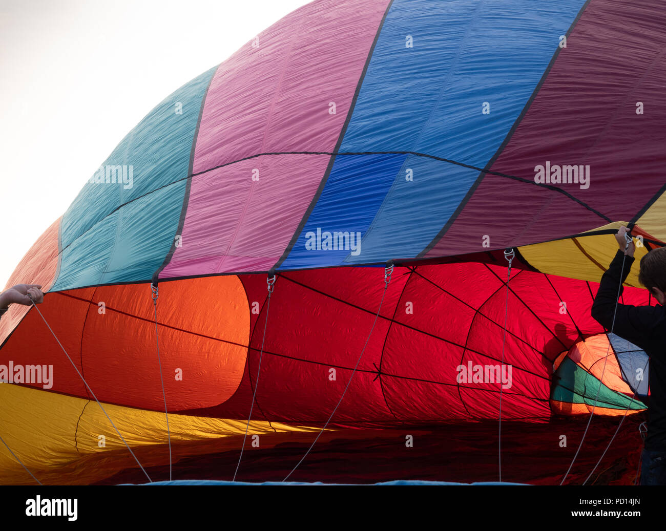 Two people holding a colorful hot air balloon as it is being inflated ...