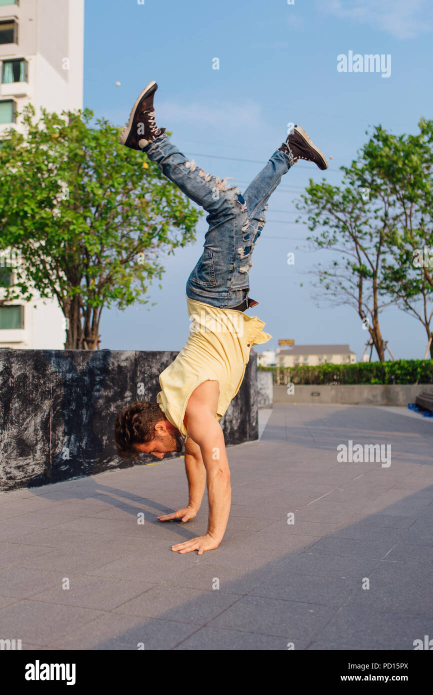 Young handsome man with beard dancing breakdance on the street. Man ...