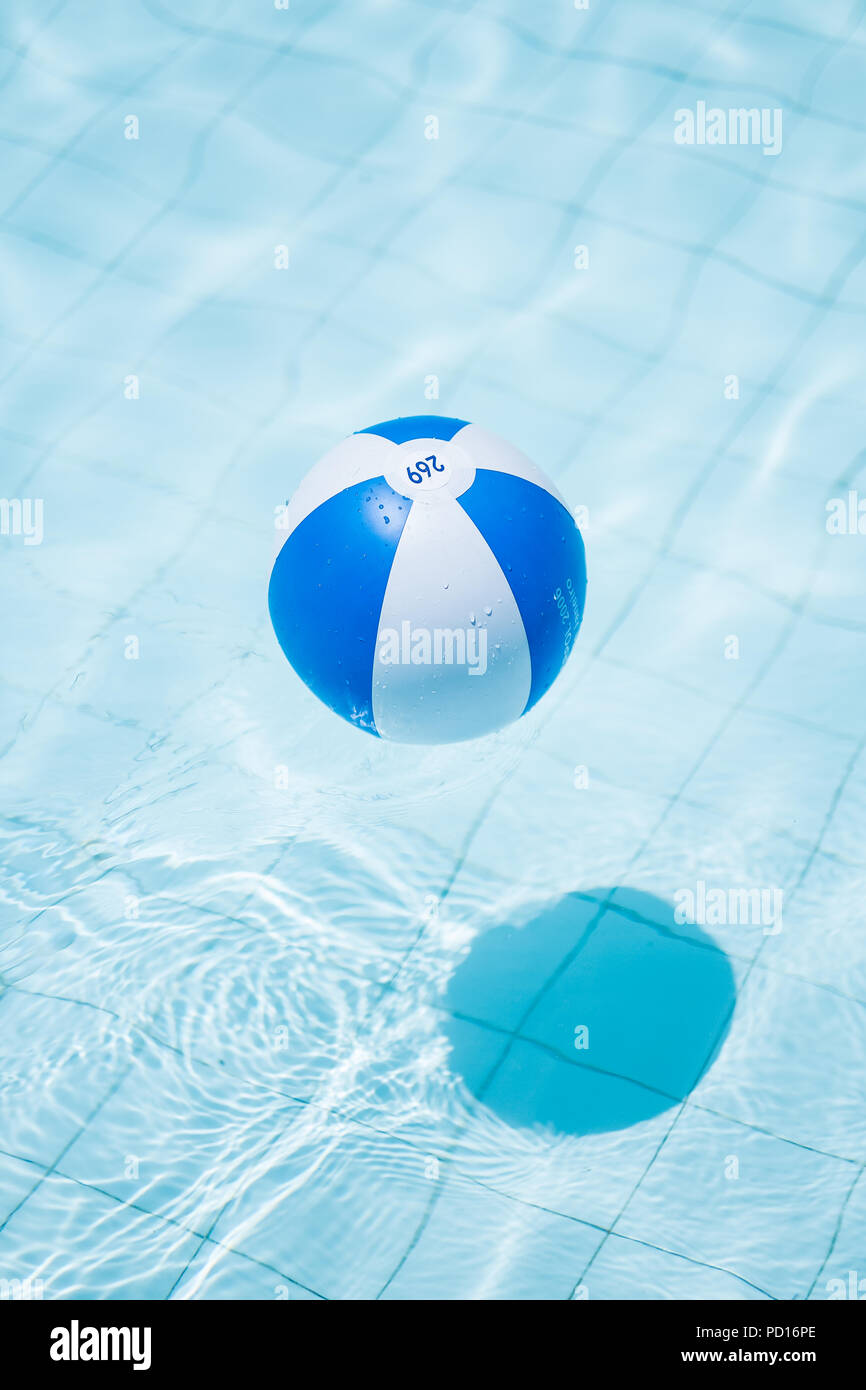 Blue and white inflatable ball floating on swimming pool under the ...