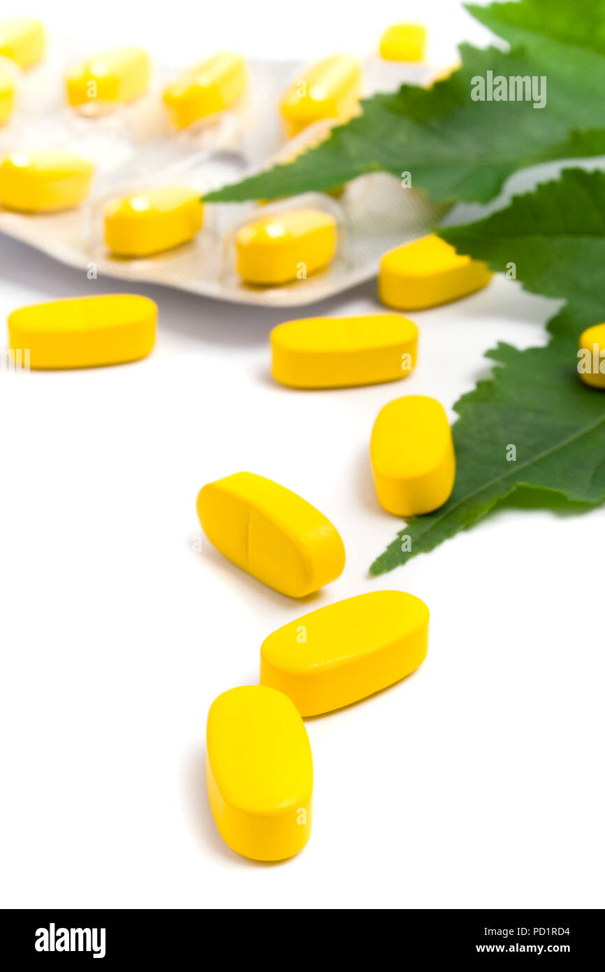 yellow vitamin pills and green leaves on white background Stock Photo ...