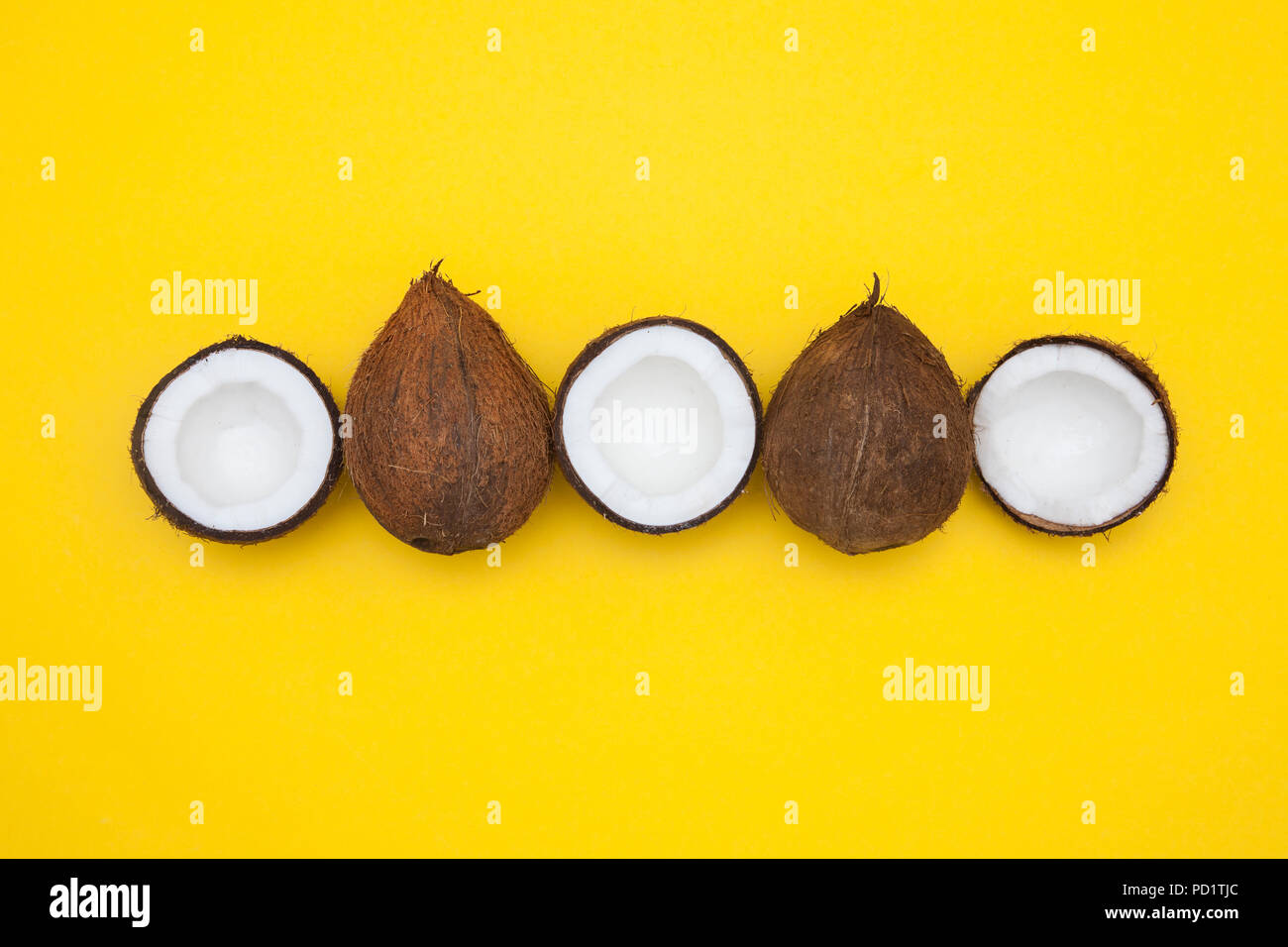 Tropical summer coconut background. half and whole coconuts on a yellow ...