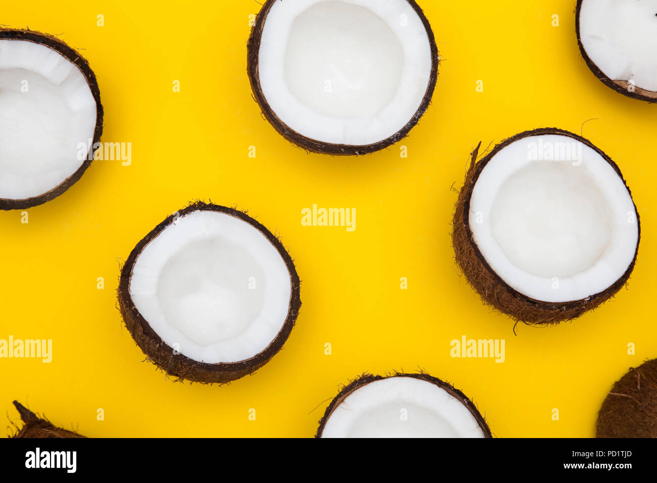 Tropical summer coconut background. half and whole coconuts on a yellow ...