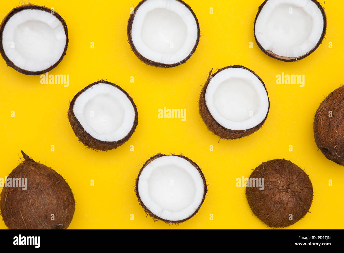 Tropical summer coconut background. half and whole coconuts on a yellow ...