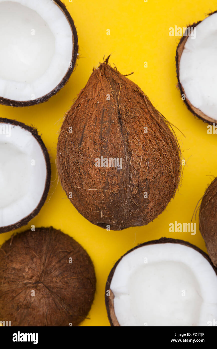 Tropical summer coconut background. half and whole coconuts on a yellow ...