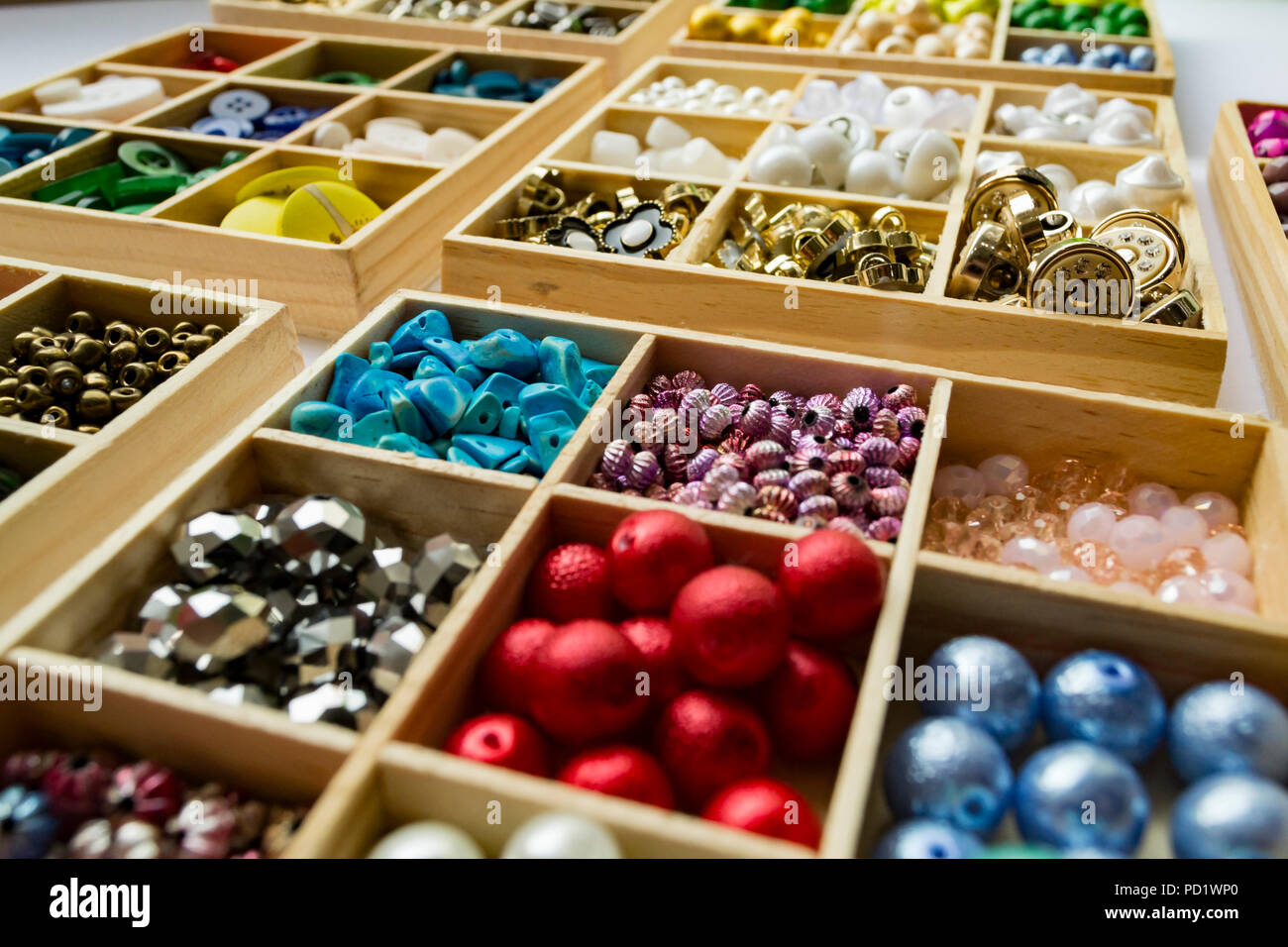 Clothes buttons in wooden boxes on white cardboard background. Closeup ...