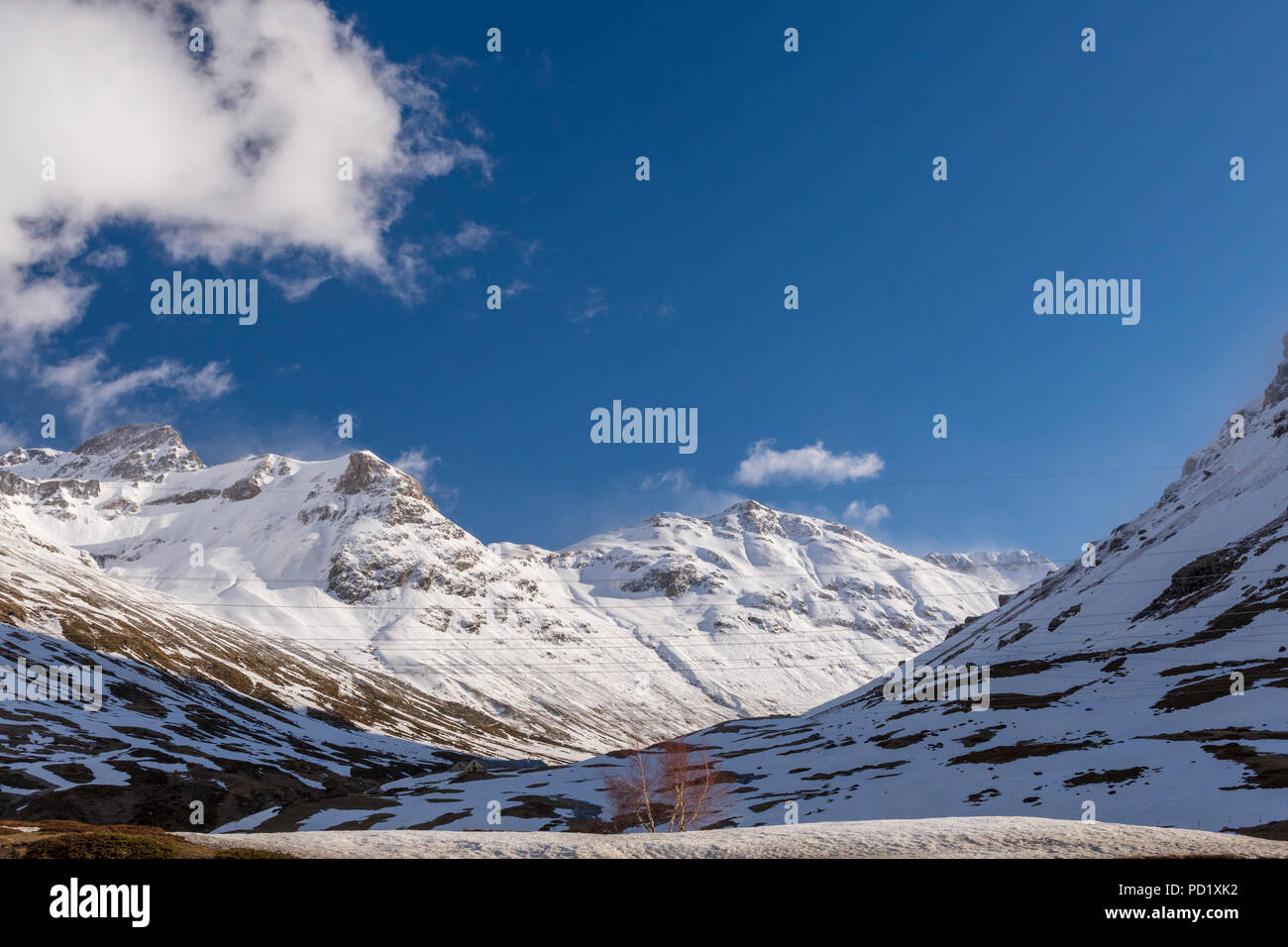 Bernina alps in spring time with three peaks against hte blue sky ...