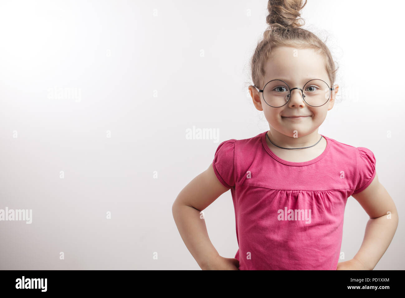clever kid with hairbun posing to the camera. genius little girl in ...