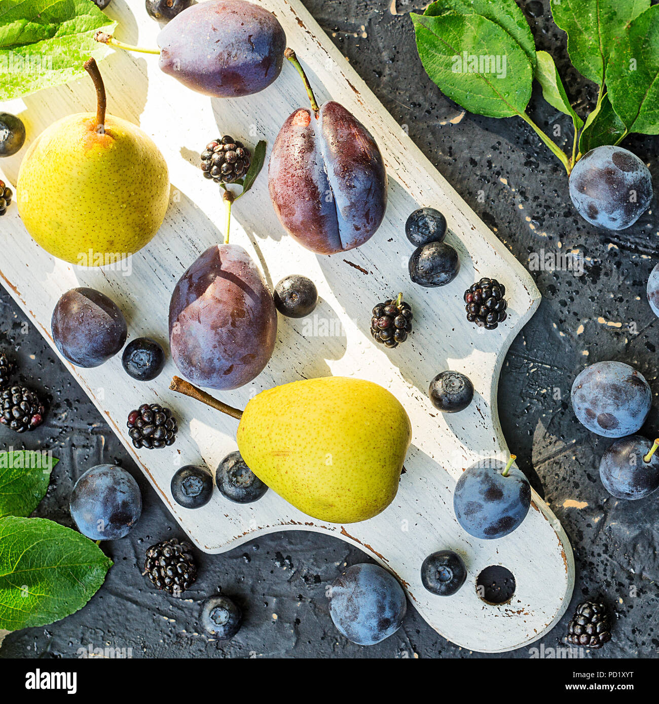 Pears and plums on a white kitchen board Stock Photo - Alamy