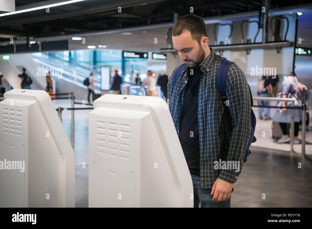 happy man using the check-in machine at the airport getting the ...