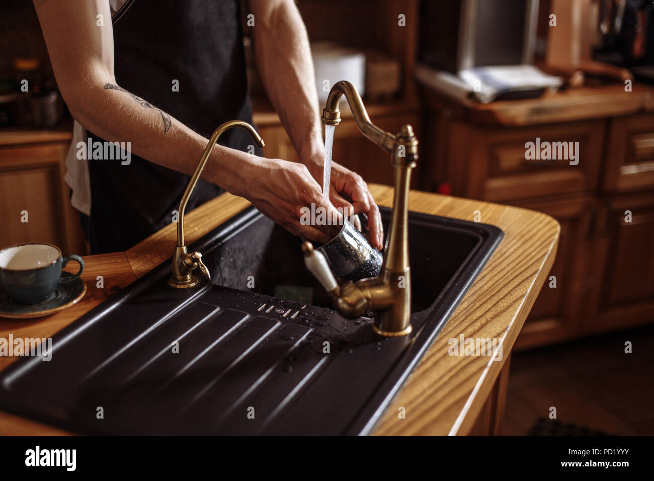 a guy is washing the dishes in the kitchen with modern interior. close ...