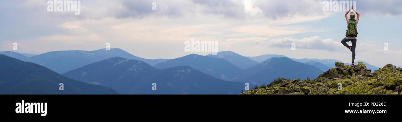 Back view of young slim tourist girl with backpack standing on one leg ...