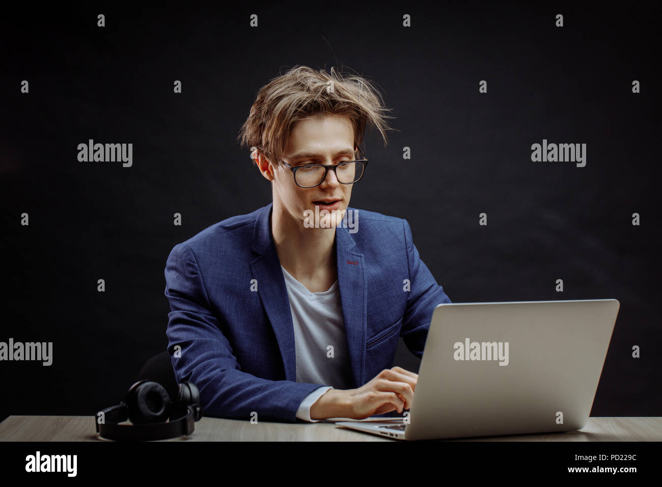 Funny young man with long brown tousled hair using a computer on black ...