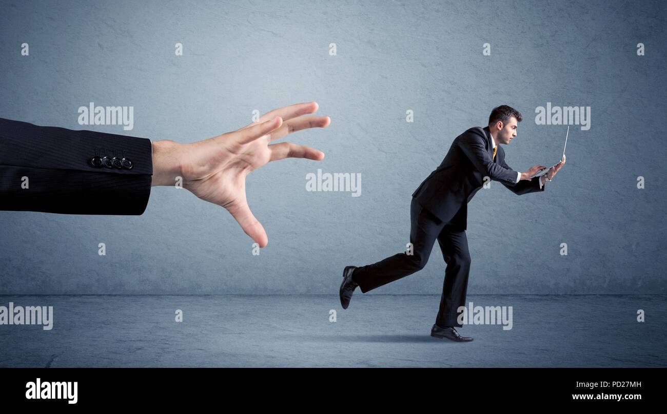 Young miniature businessman running from a big hand with blue ...